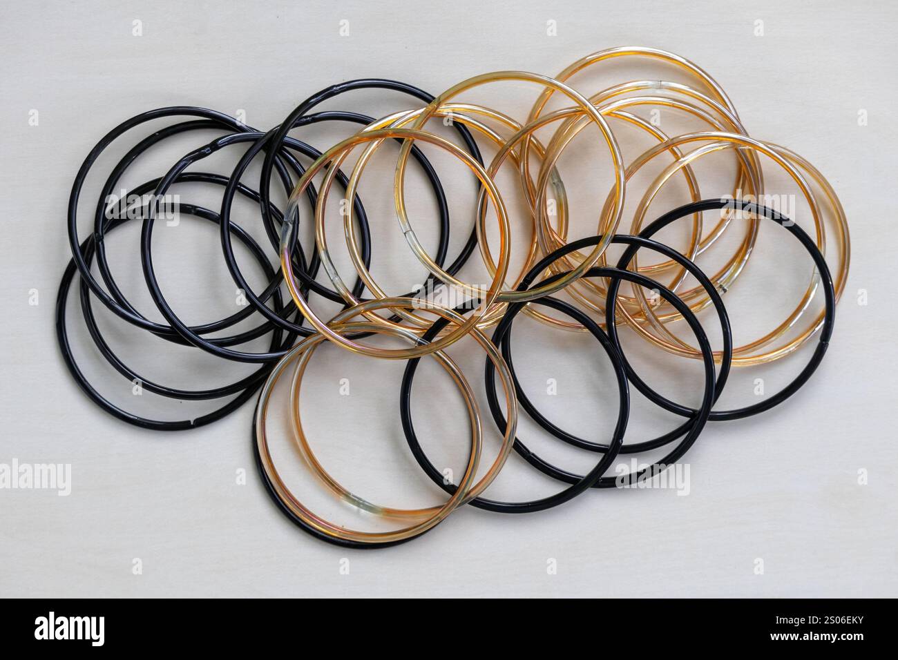 Black and gold glass bangles scattered on a wooden tile background ...