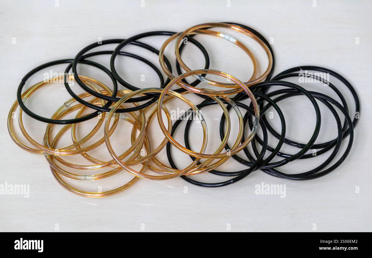 Black and gold glass bangles scattered on a wooden tile background ...