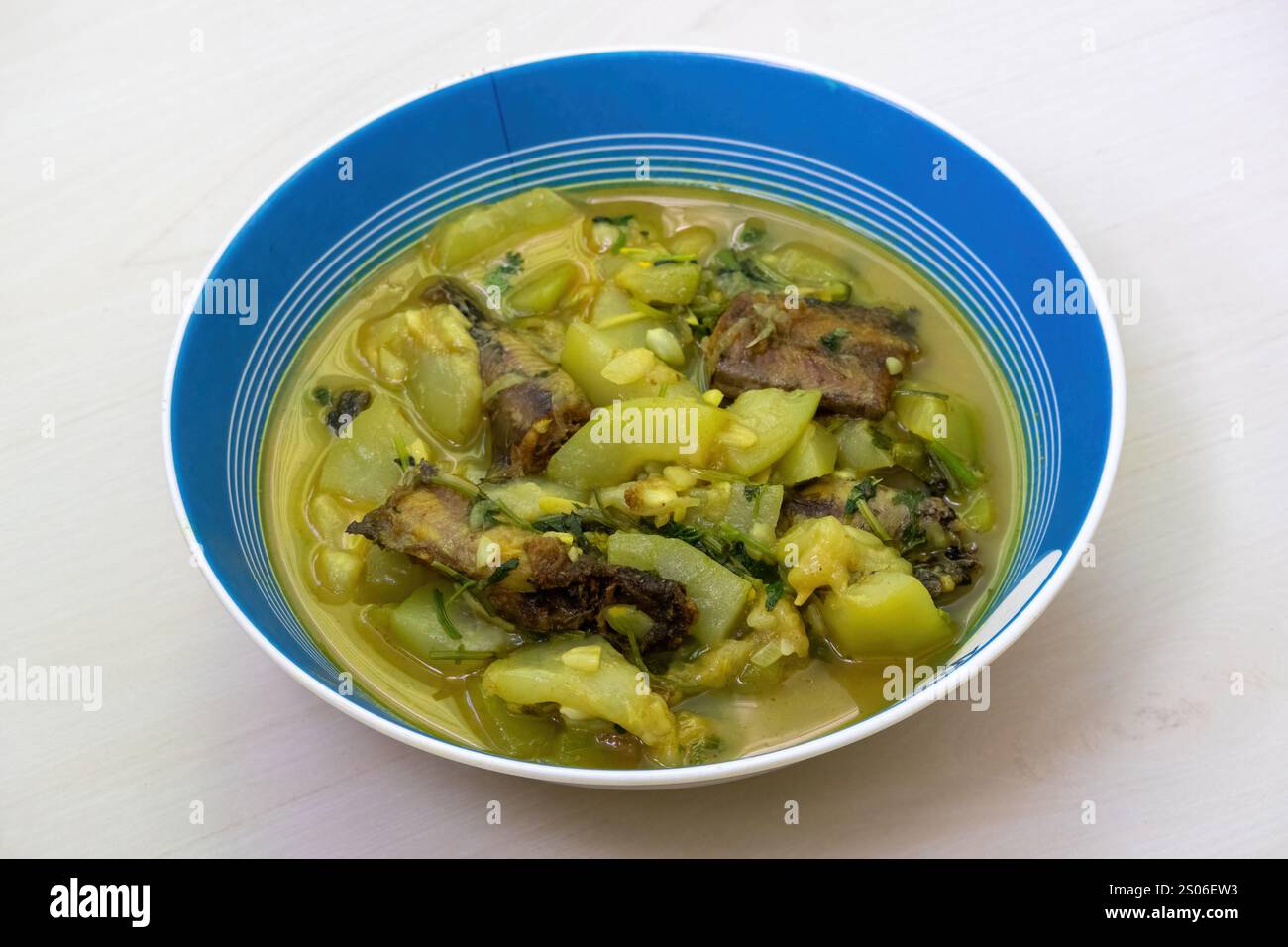 A bowl of cooked shing fish curry with gourd. Shing mach is a popular ...