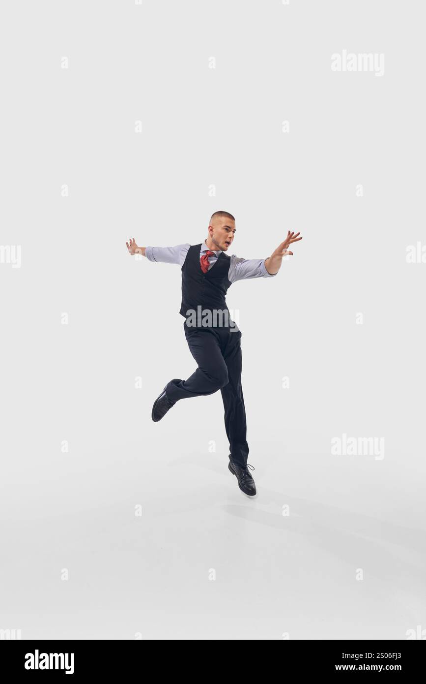 Man in formal attire leaps mid-air with arms extended outward and ...