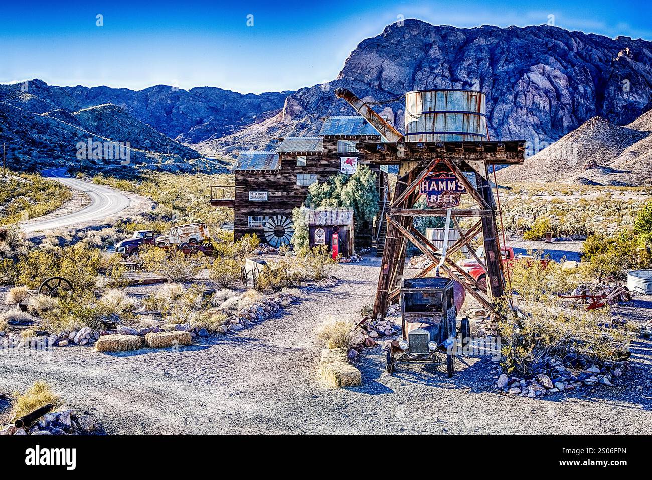A desert scene with a shack and a water tower. The shack is old and the ...
