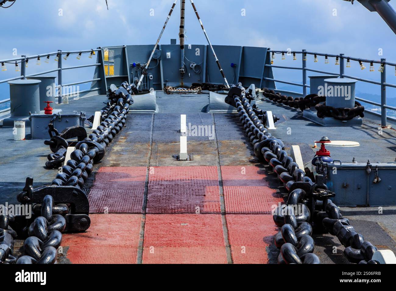 A large ship with a red and black chain link walkway. The walkway is ...