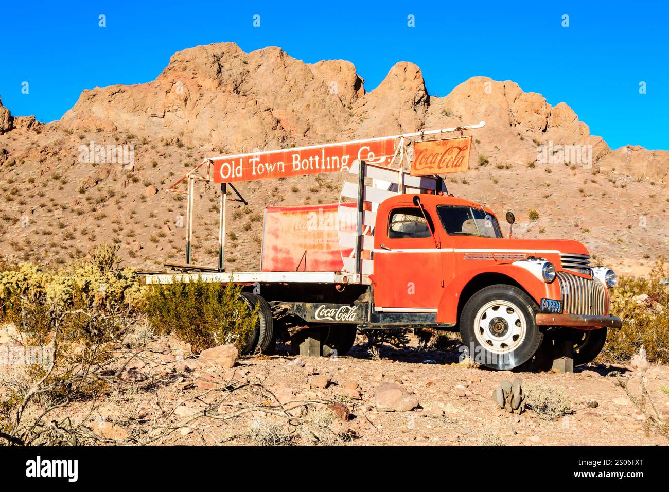 An old Coca-Cola truck is parked in the desert. The truck is red and ...