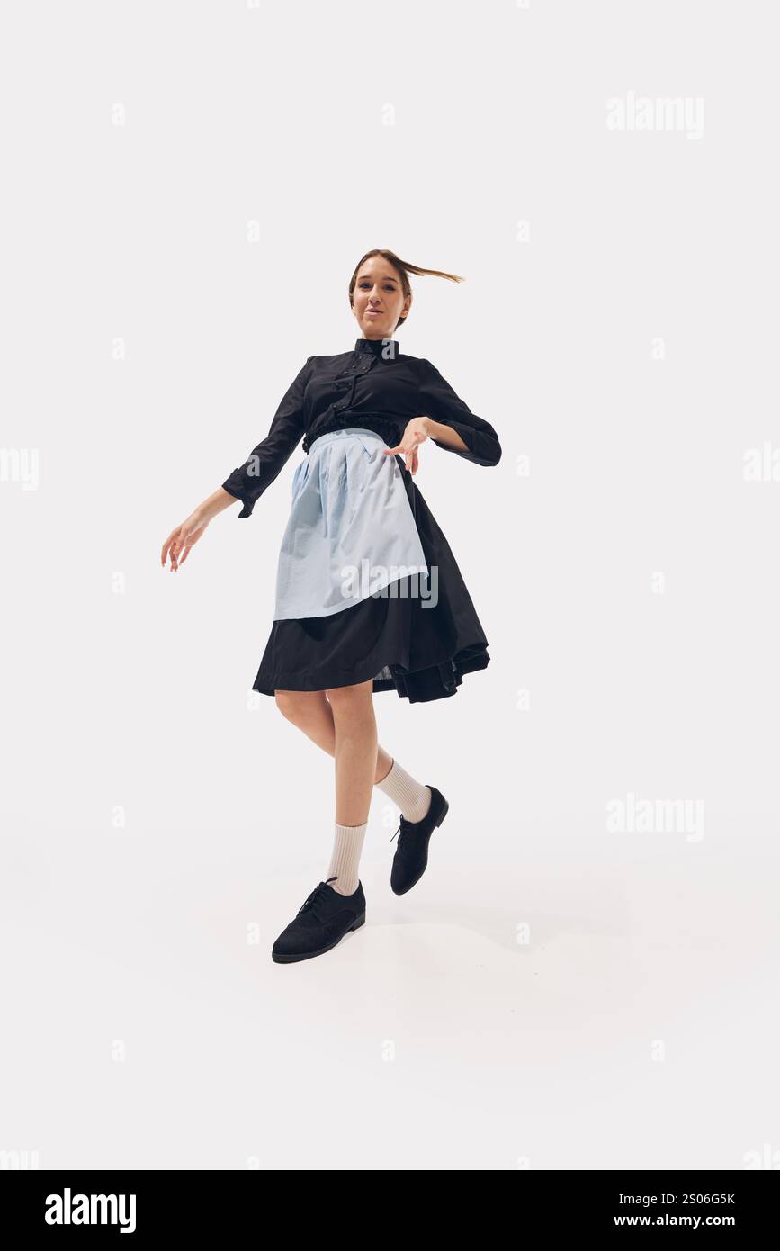 Female waiter in black uniform and apron standing confidently, hair ...