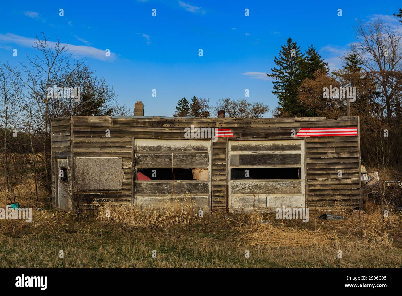 A run down old building with a red stripe on the side. The building is ...