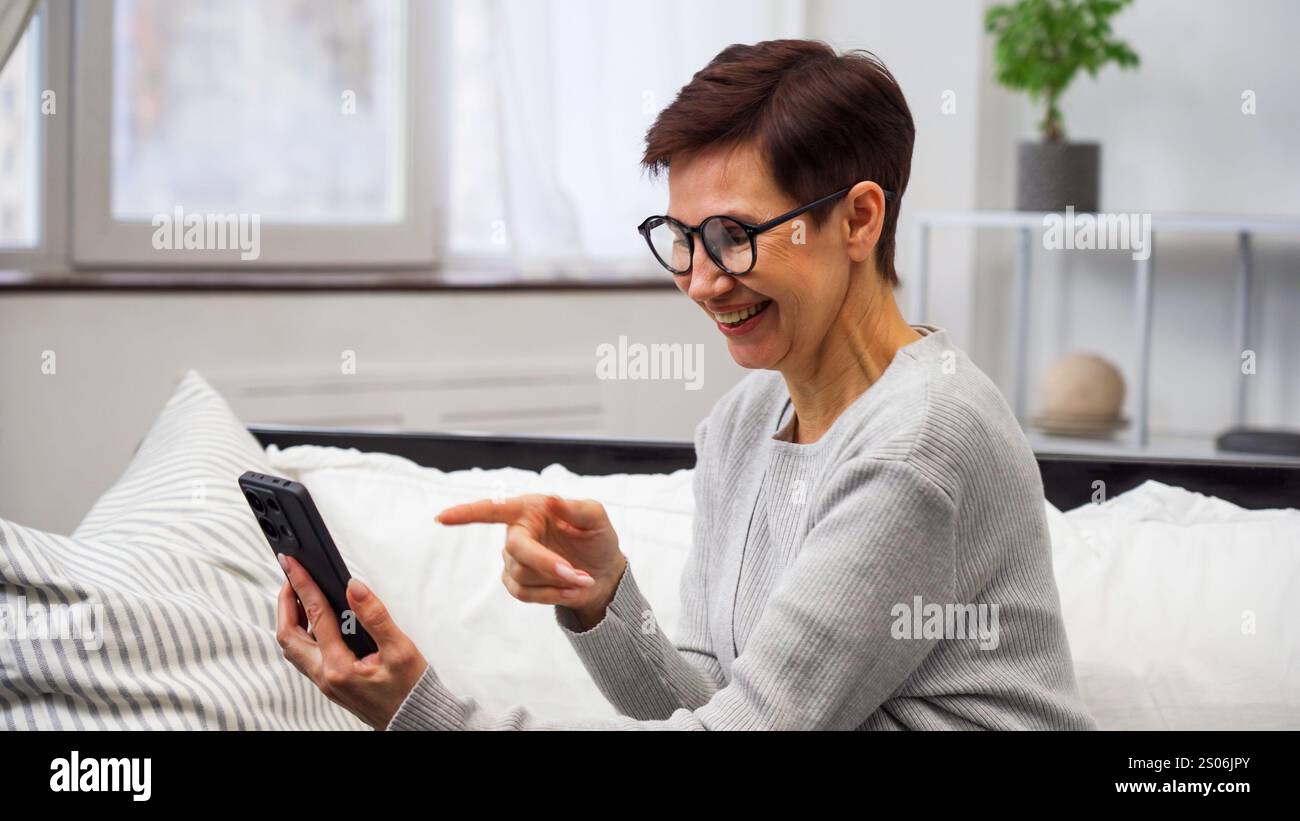 Relaxed woman smiles and points at the screen during a fun and friendly ...