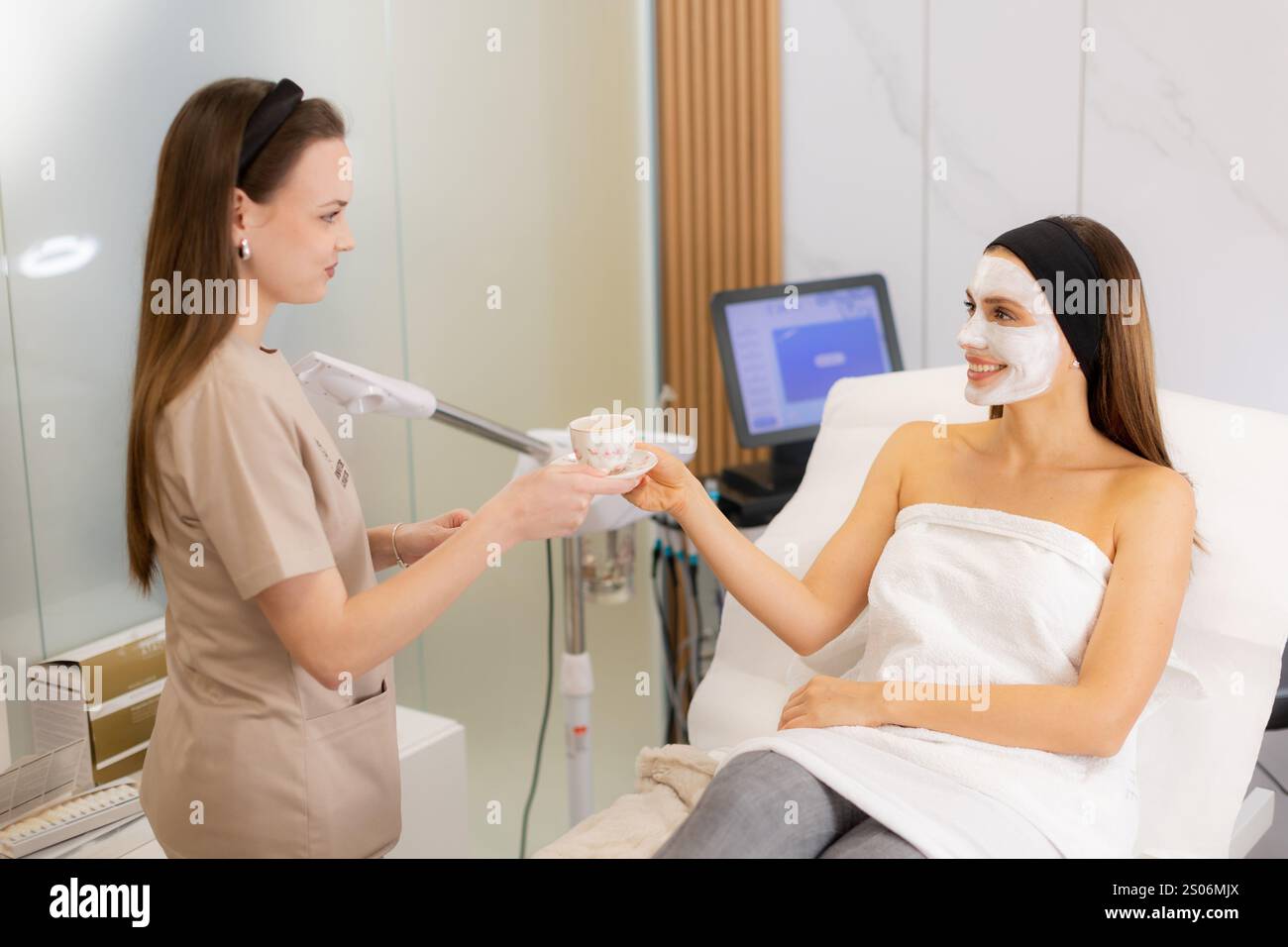 In a serene spa setting, a woman with a facial mask sits back on a ...