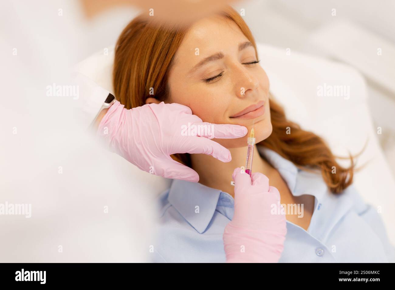 A skilled practitioner applies lip filler to a relaxed client in a calm ...