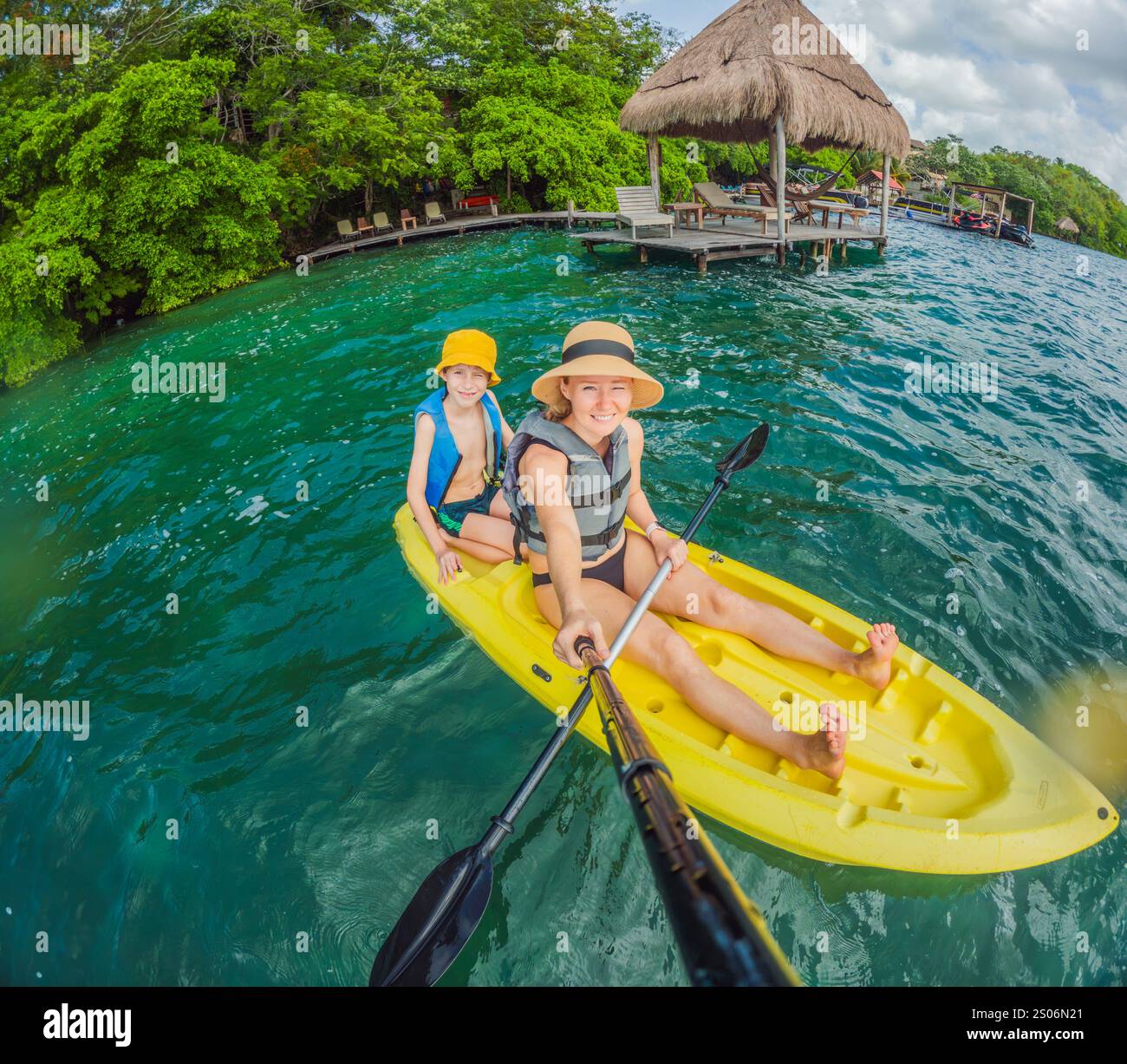 Mother and son tourists kayaking together on the crystal-clear ...
