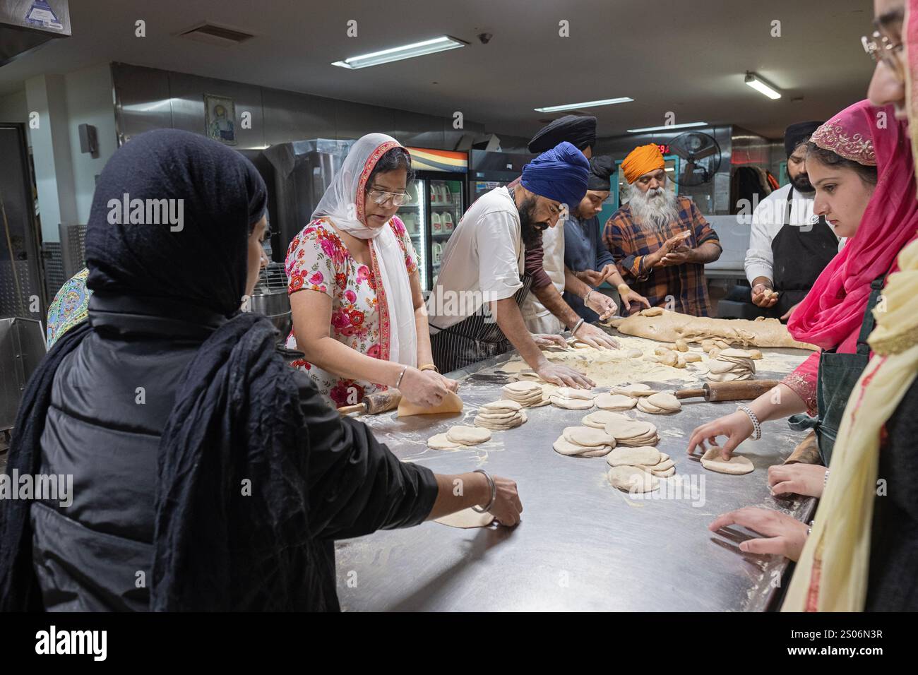 Sikh men & women of various ages make roti breads in a langar, free ...