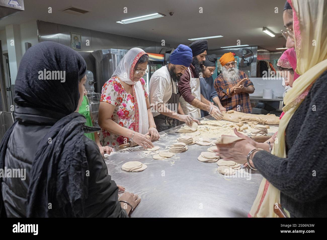 Sikh men & women of various ages make roti breads in a langar, free ...