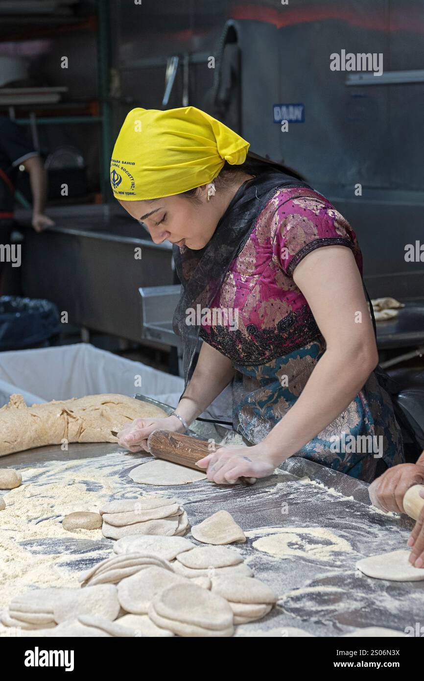 Young attractive Sikh woman rolls dough while making roti breads in a ...