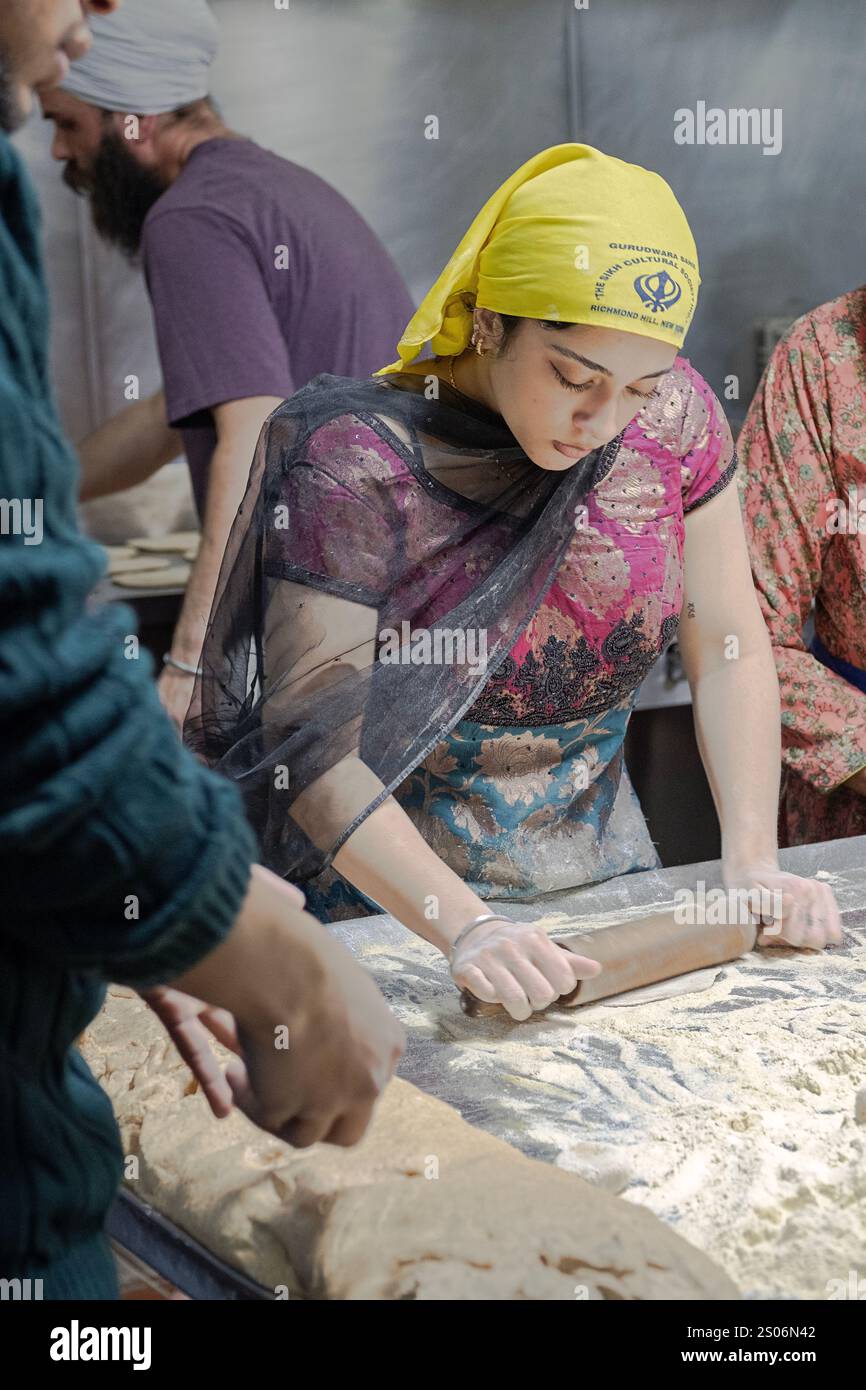 Young attractive Sikh woman rolls dough while making roti breads in a ...