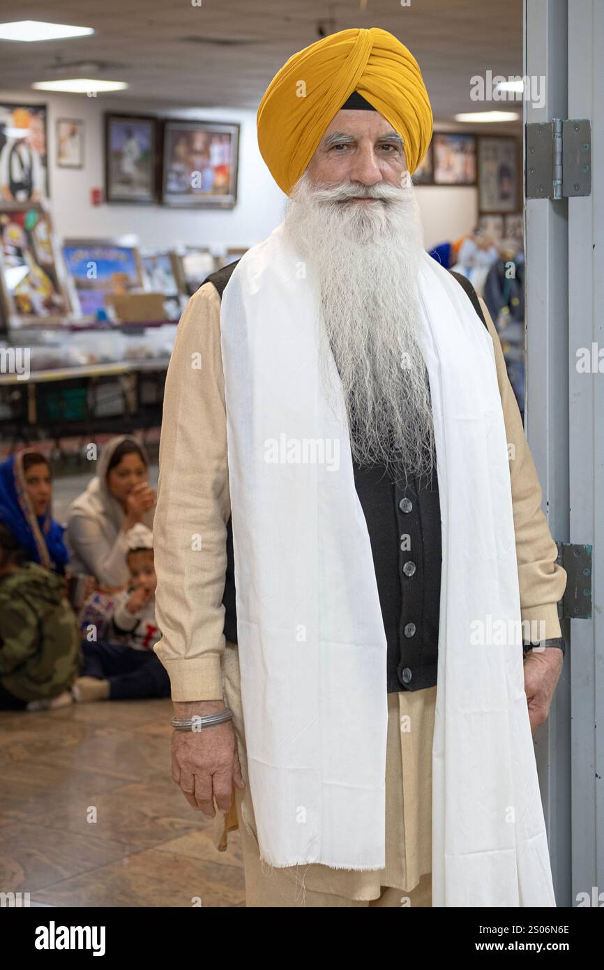 A distinguished older Sikh man wearing a yellow dastar turban and a ...