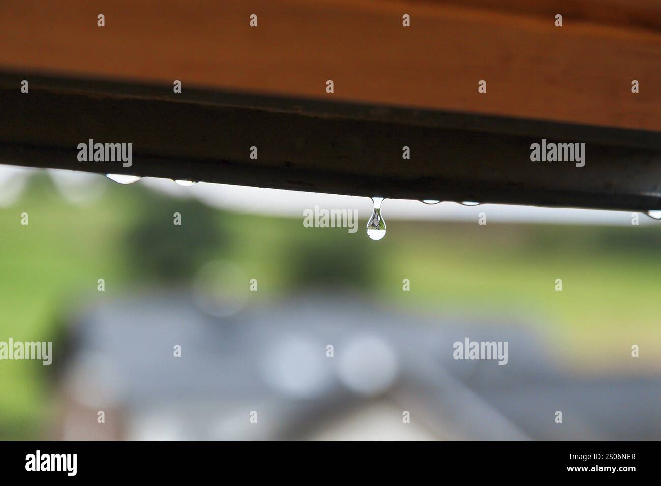 Tiny raindrop hangs on window frame, house reflected, symbol photo ...