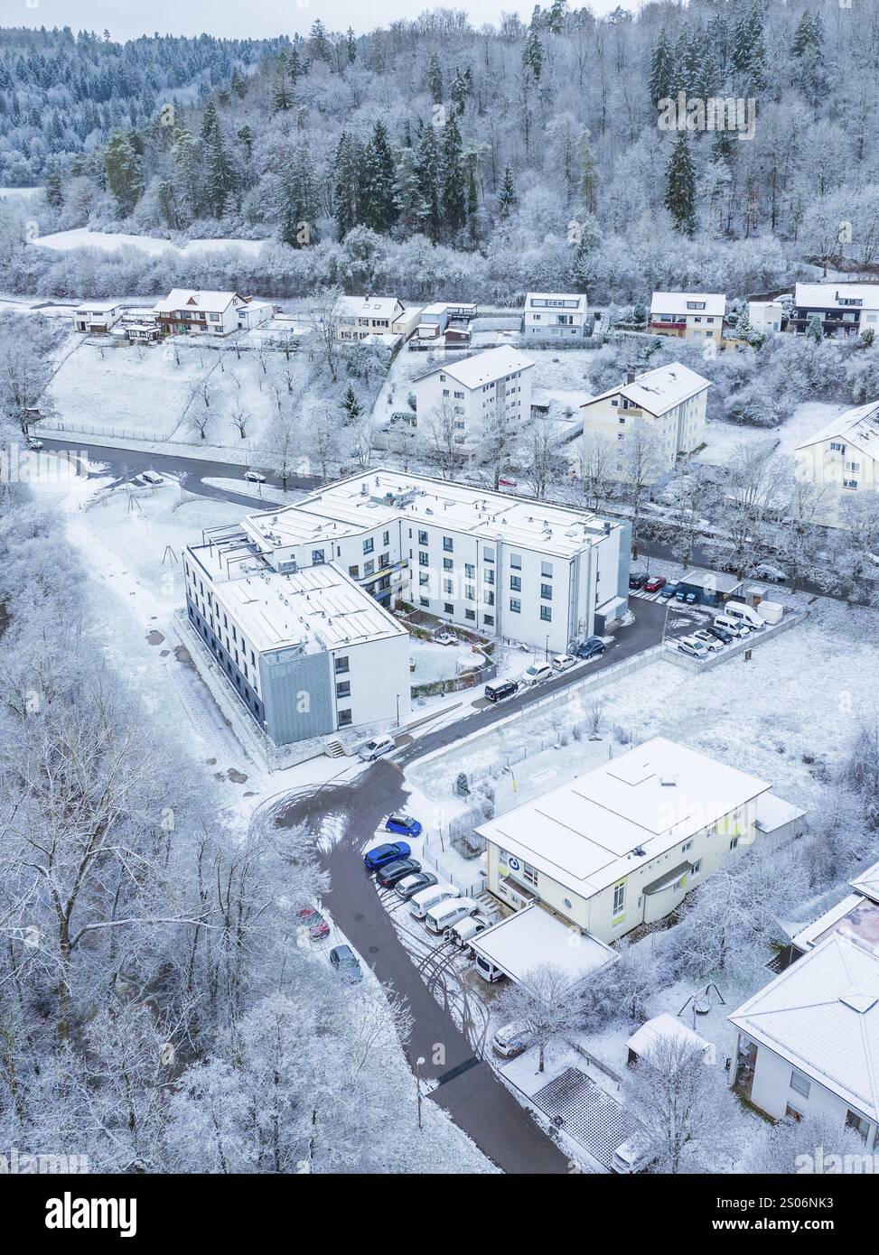Snowy village scenery with modern buildings surrounded by forests and ...