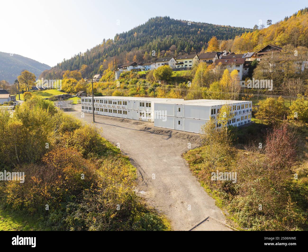 Container building in front of an autumnal hill with a village in the ...