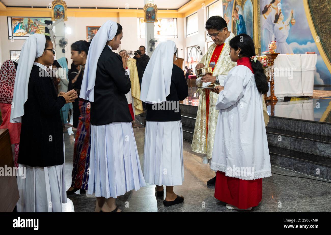 Guwahati, India. 25th Dec 2024. Devotees take holy communion from a ...