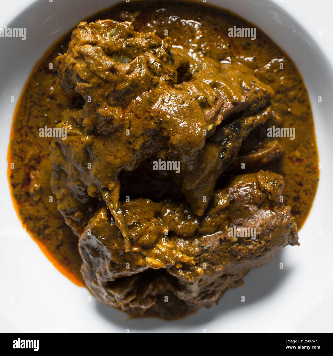 Overhead view of Nigerian banga soup with fish and beef in a white ...