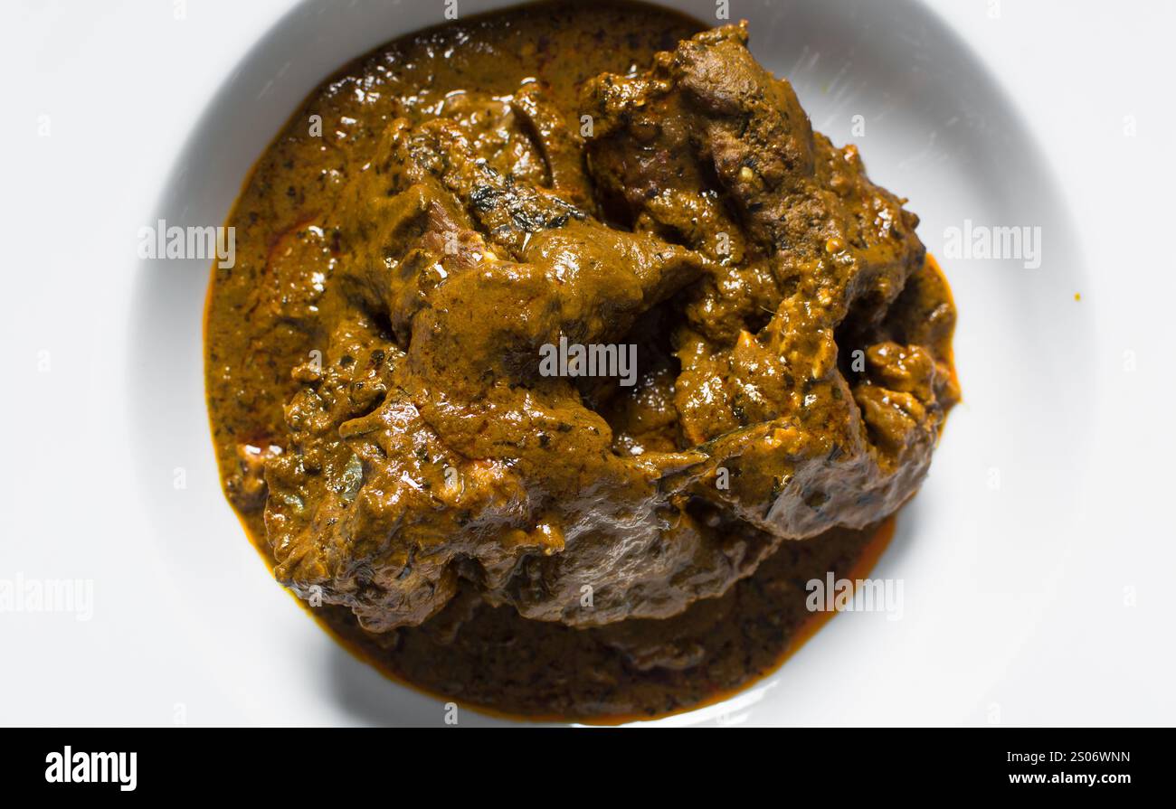 Overhead view of Nigerian banga soup with fish and beef in a white ...