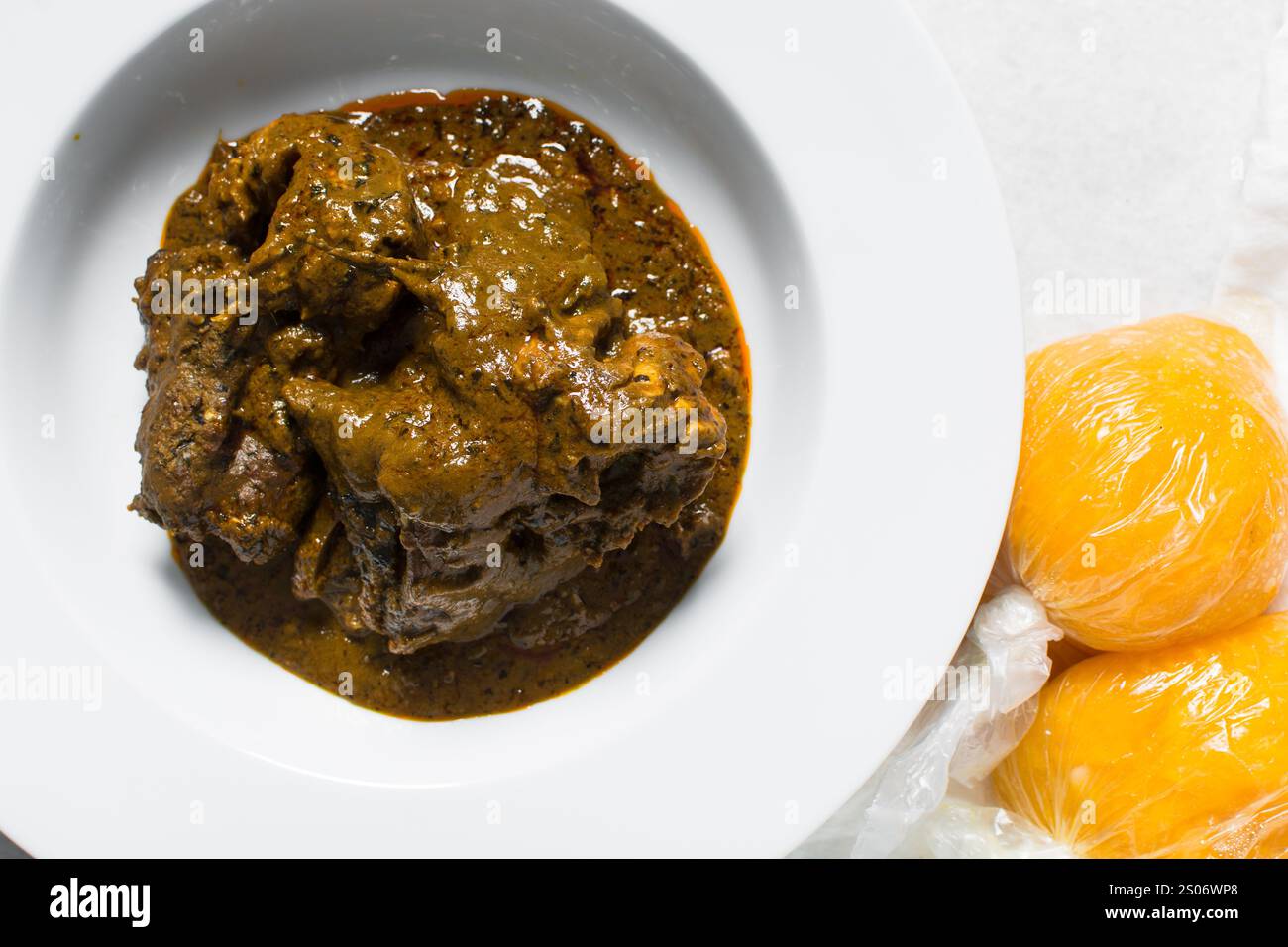 Overhead view of Nigerian banga soup with fish and beef in a white ...