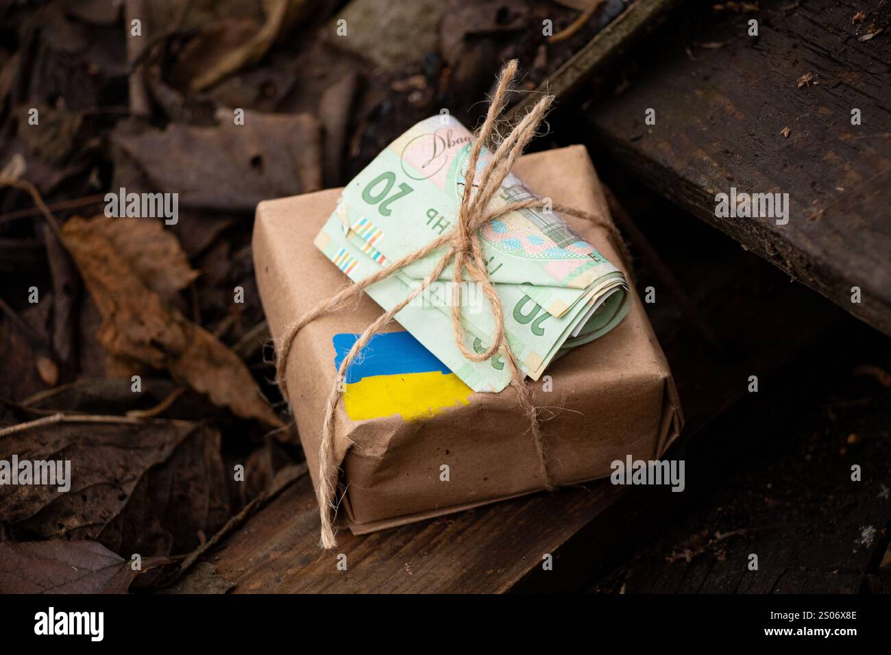 Gift box and Ukrainian flag with hryvnias lying on the ground in ...