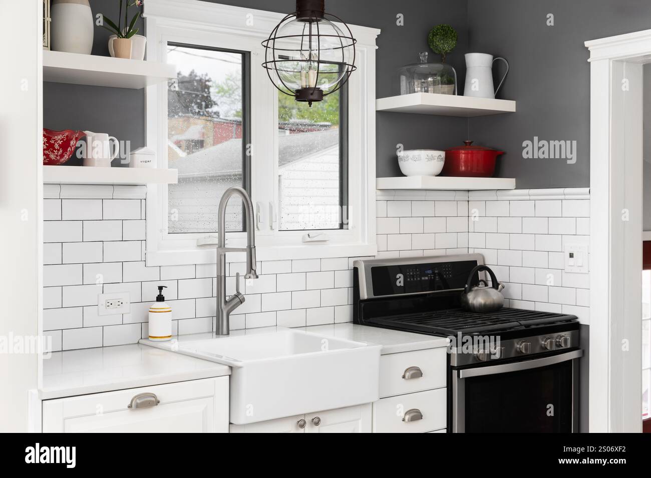 A kitchen faucet detail with white cabinets, farmhouse sink in front of ...
