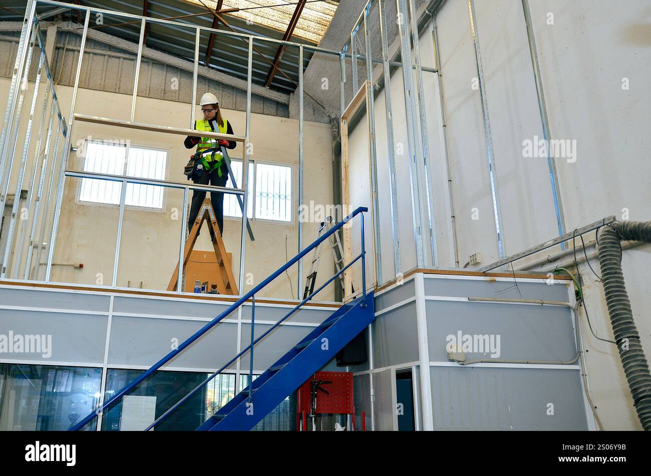 Female construction worker mounting plasterboard on metal frame using ...