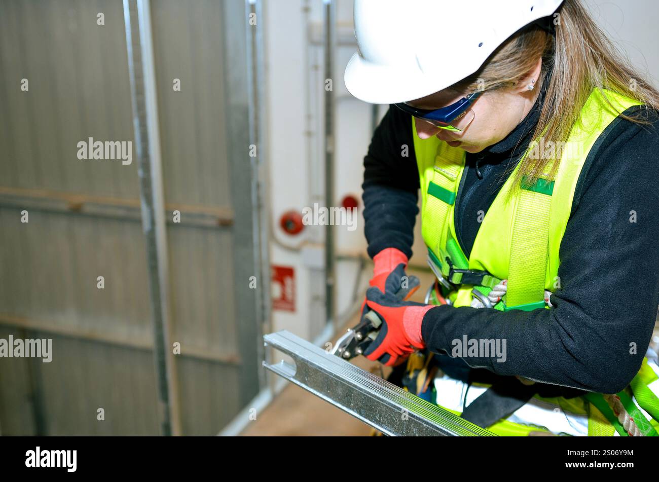 Female construction worker cutting metal profile for plasterboard ...
