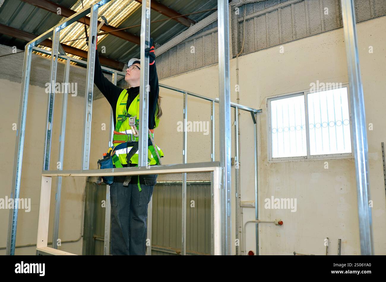 Female construction worker assembling metal frame for plasterboard wall ...