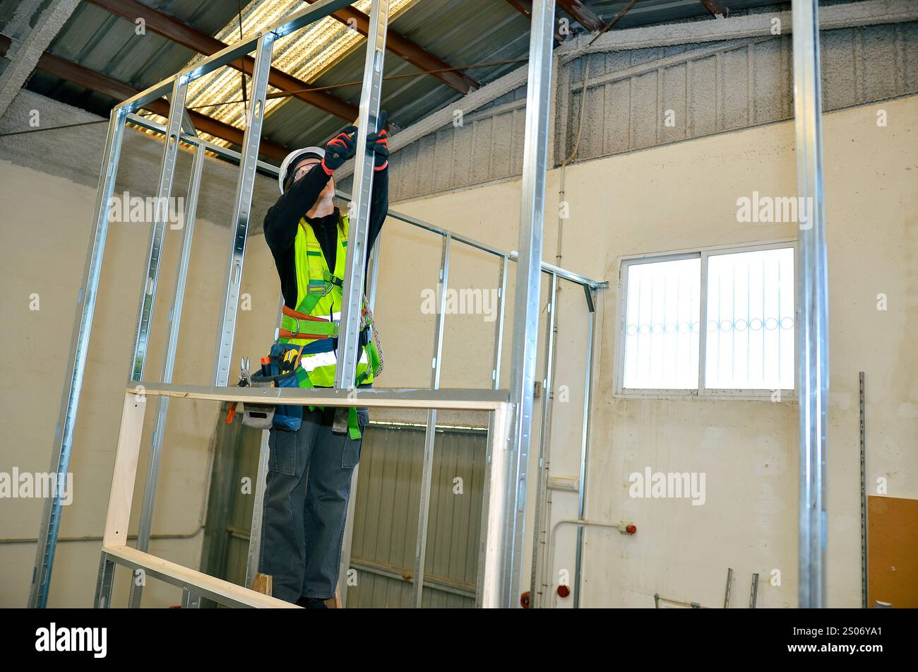 Builder mounting plasterboard on metal frame working on interior wall ...