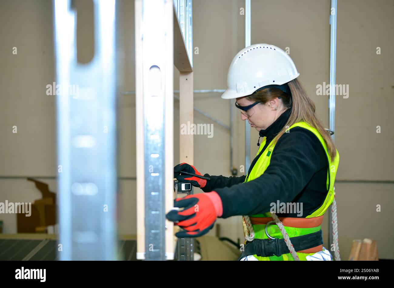 Female construction worker using spirit level while mounting ...