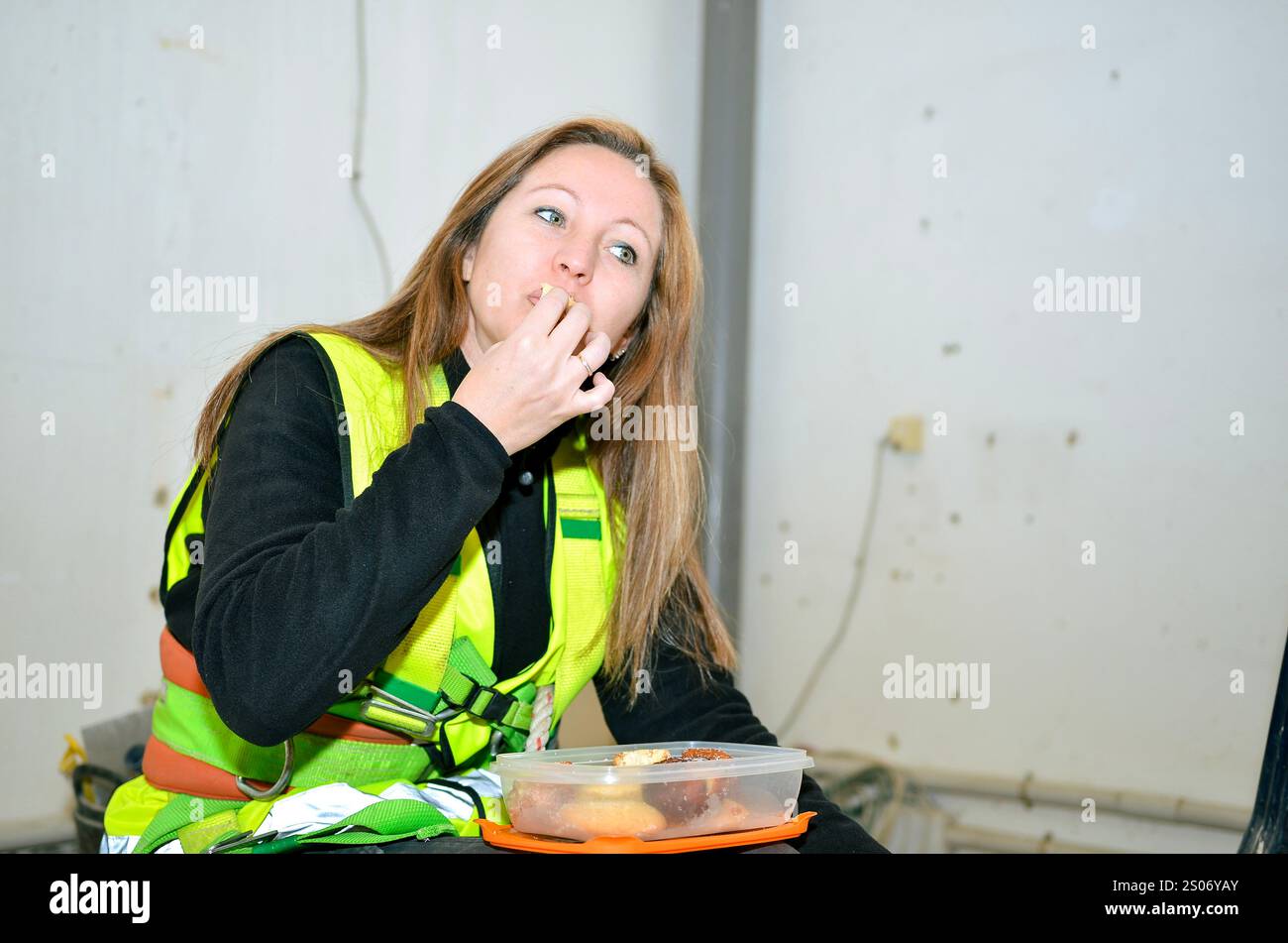 Construction worker taking a lunch break, eating cookies on a ...