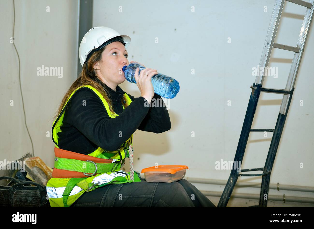 Female construction worker drinking water during break on construction site Stock Photo - Alamy