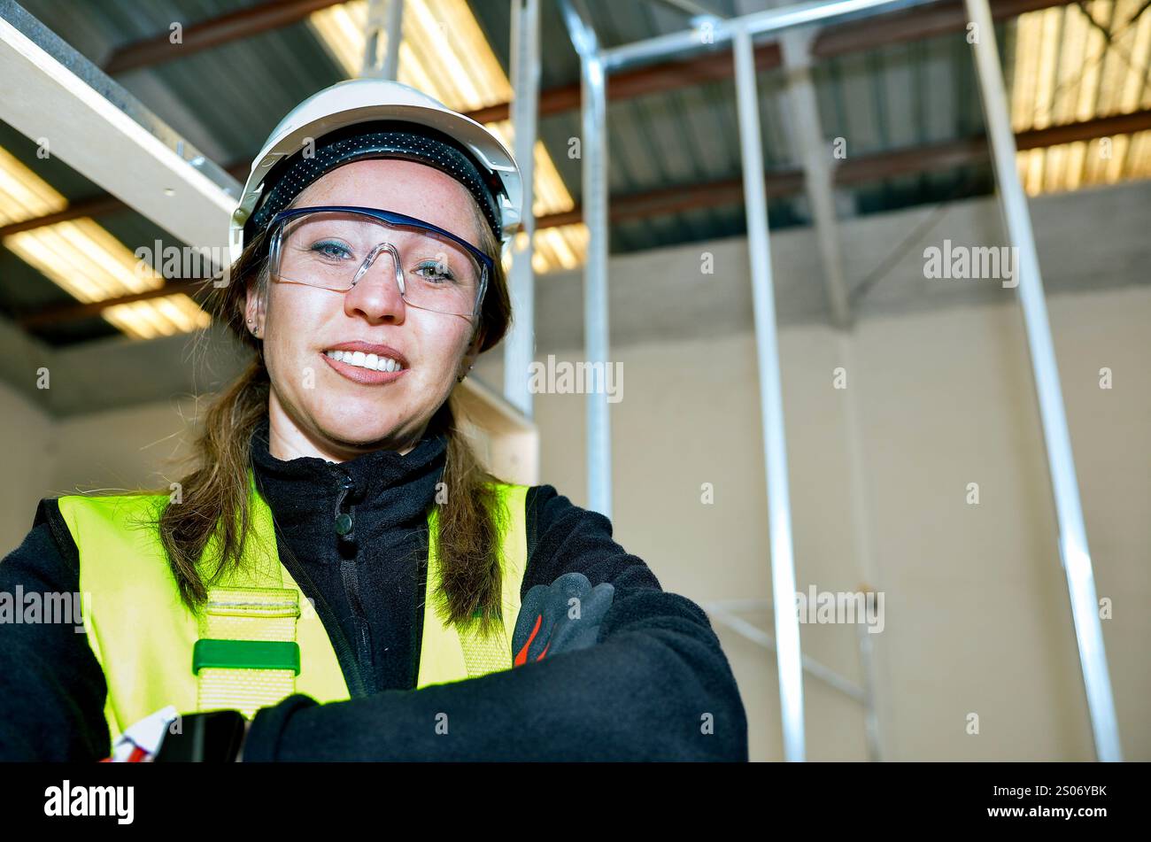 Confident construction worker smiles while mounting plasterboard to the ...