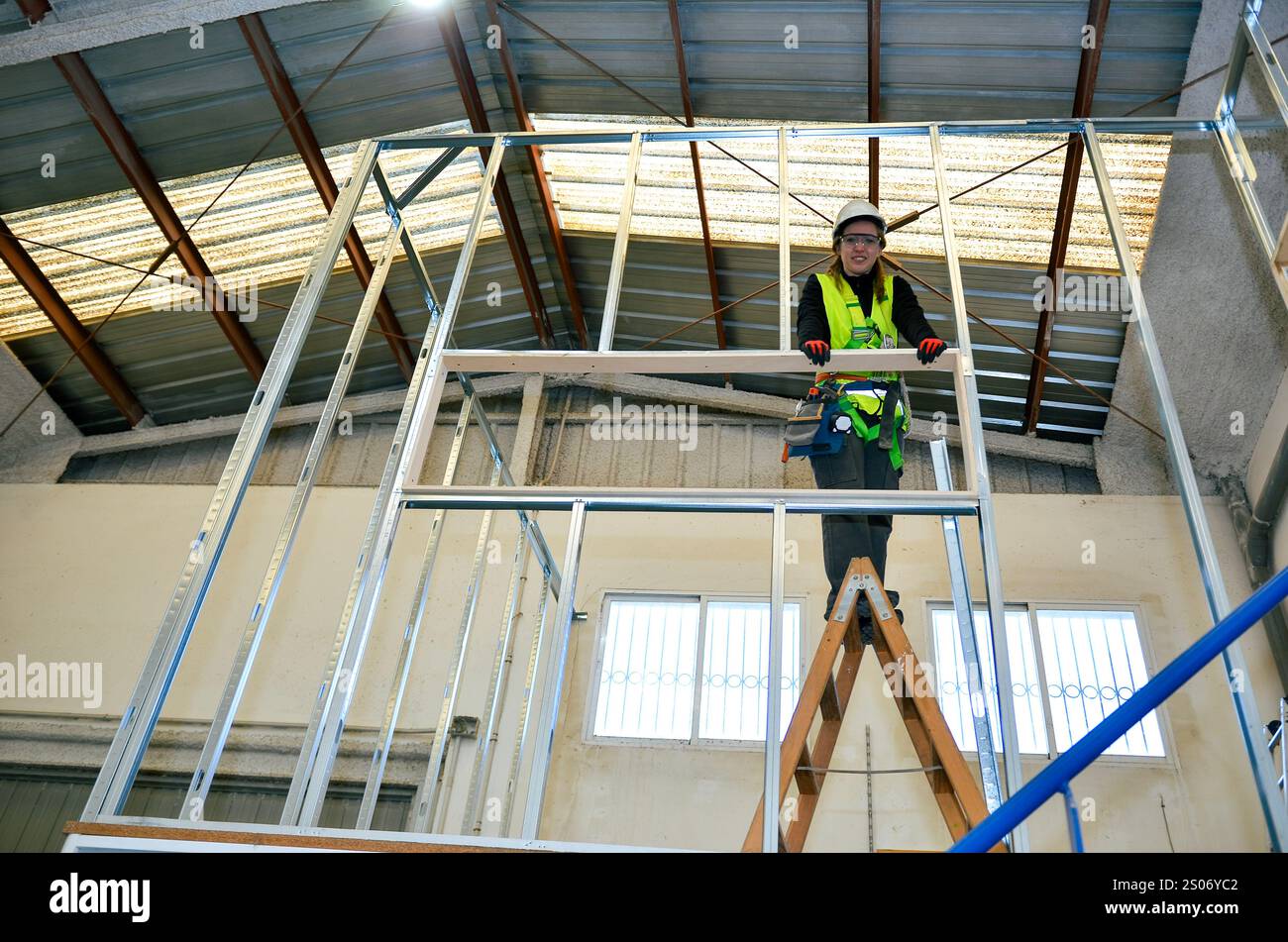 Female construction worker mounting plasterboard on metal frame using ...