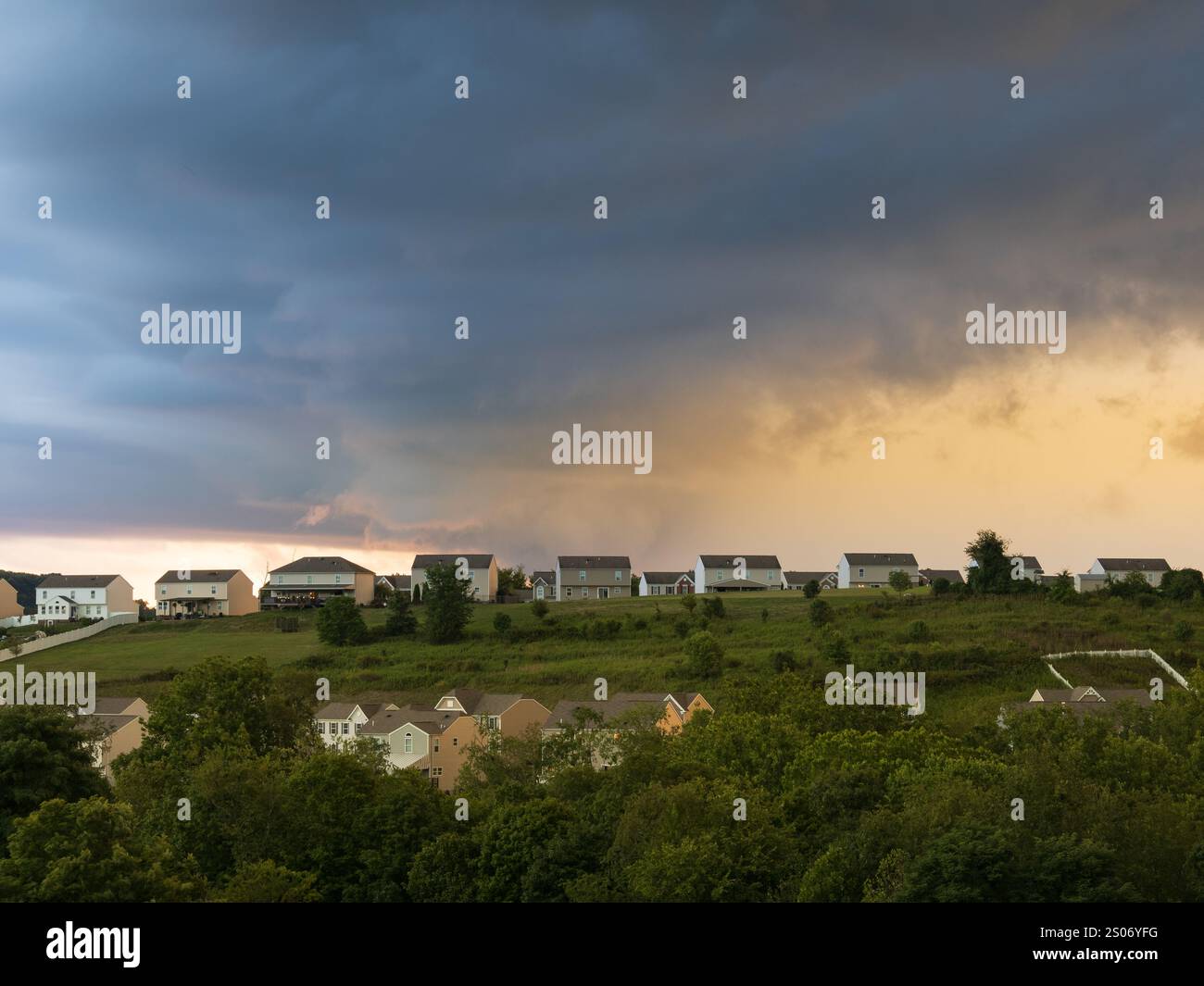 Storm clouds loom over a peaceful US neighborhood, with a bright break ...