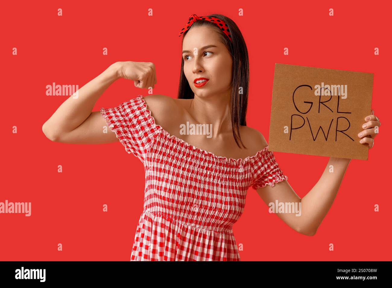 Portrait of strong pin-up woman showing muscles and holding sign with ...