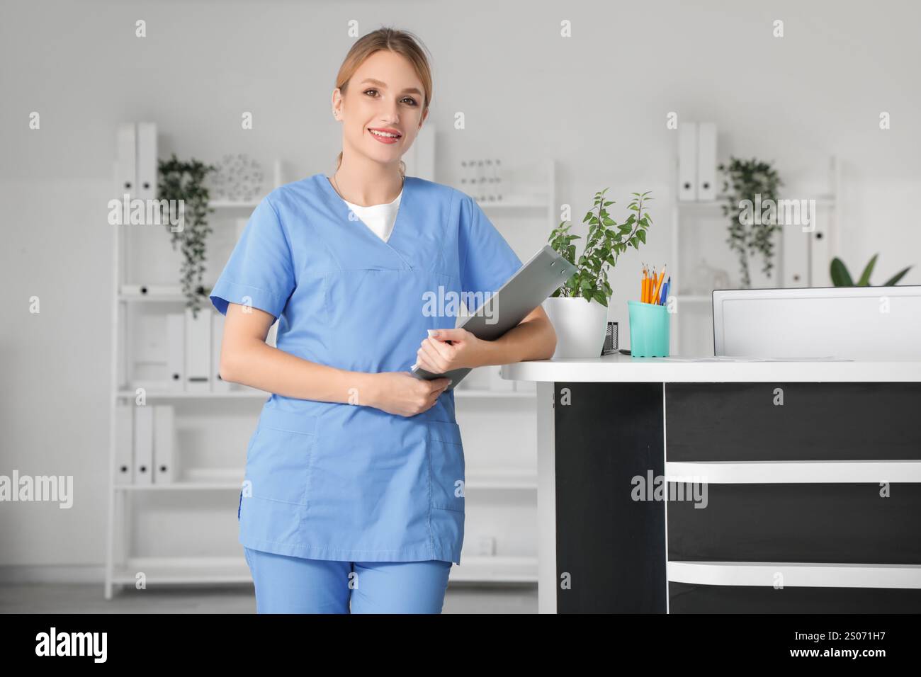 Female medical intern with clipboard near reception in clinic Stock ...