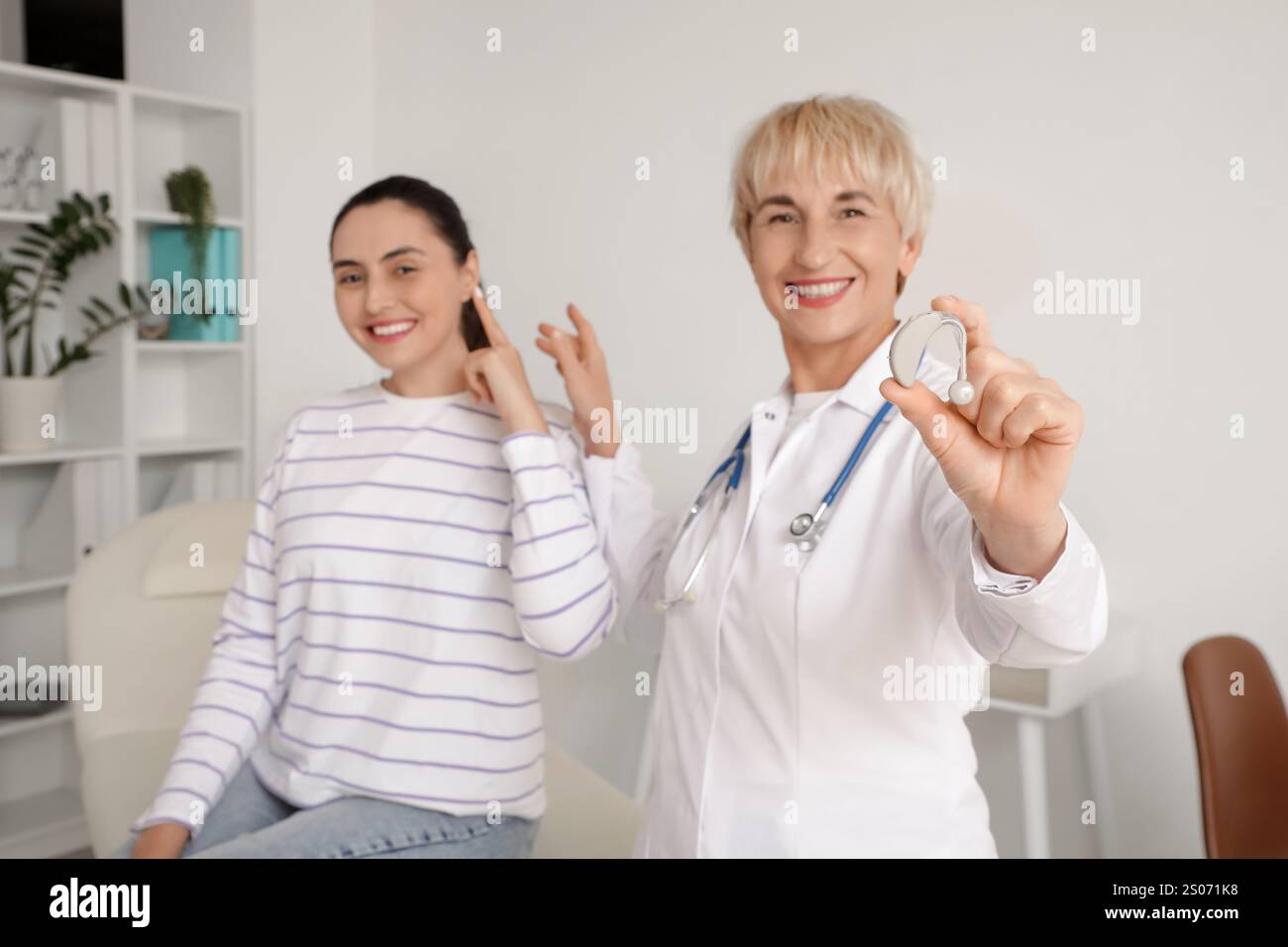 Doctor with hearing aid and young female patient in clinic Stock Photo ...