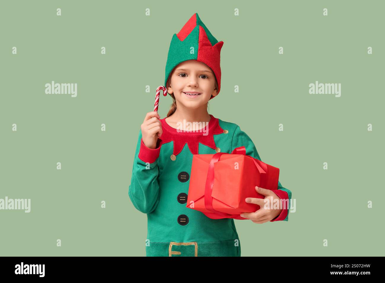 Cute little girl in elf costume with Christmas gift box and candy cane ...