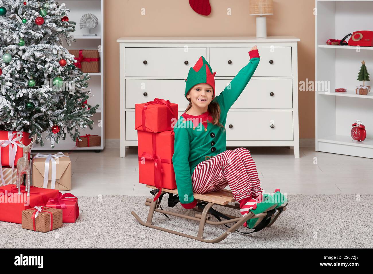 Cute little girl in elf costume with Christmas gift boxes sitting on ...