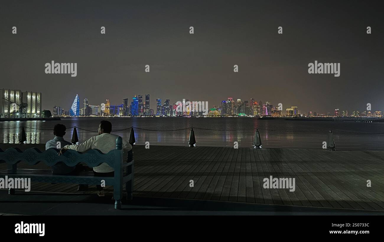 People seen sitting on a bench on the seaside promenade of Doha Stock ...