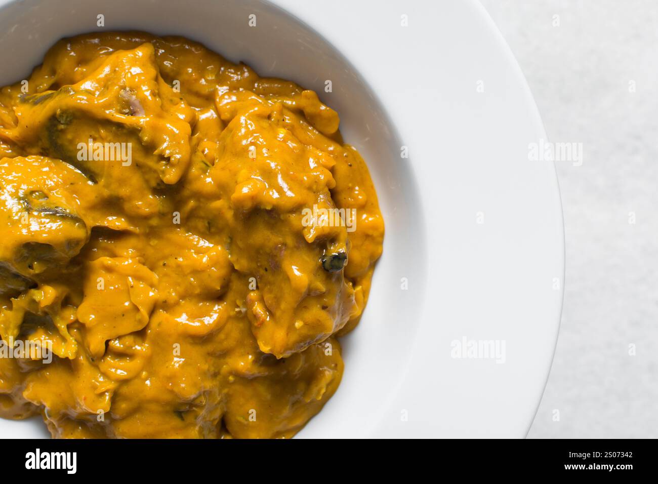 Overhead view of Nigerian owo soup with fish and beef in a white plate ...