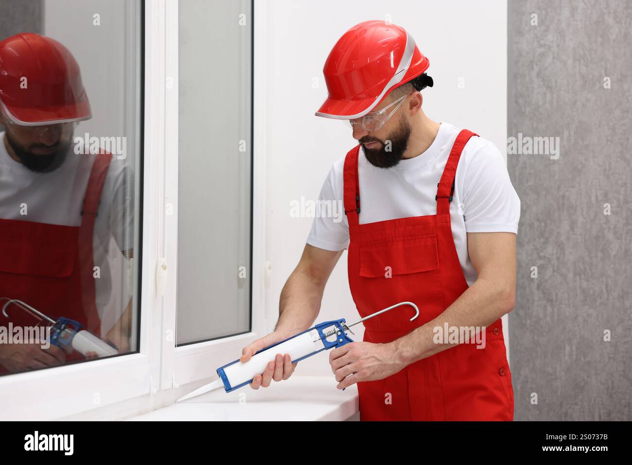 Worker with caulking gun sealing window indoors Stock Photo - Alamy