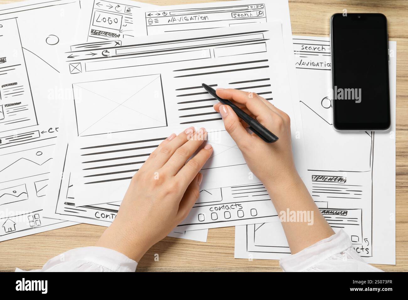 Website designer creating wireframe on paper with pen at wooden table ...