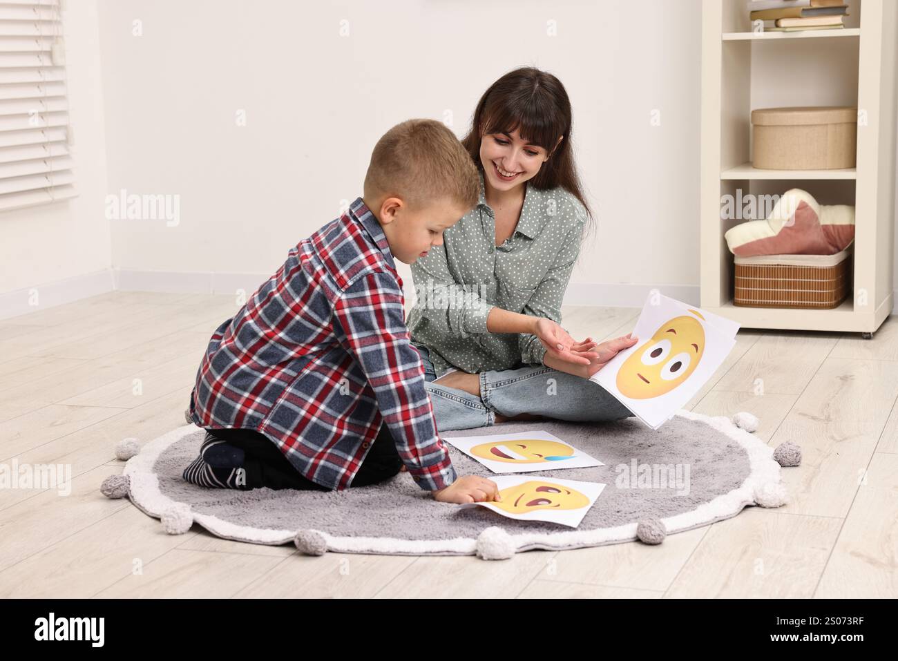 Autism therapy. Little boy choosing emoticon with smiling psychologist ...