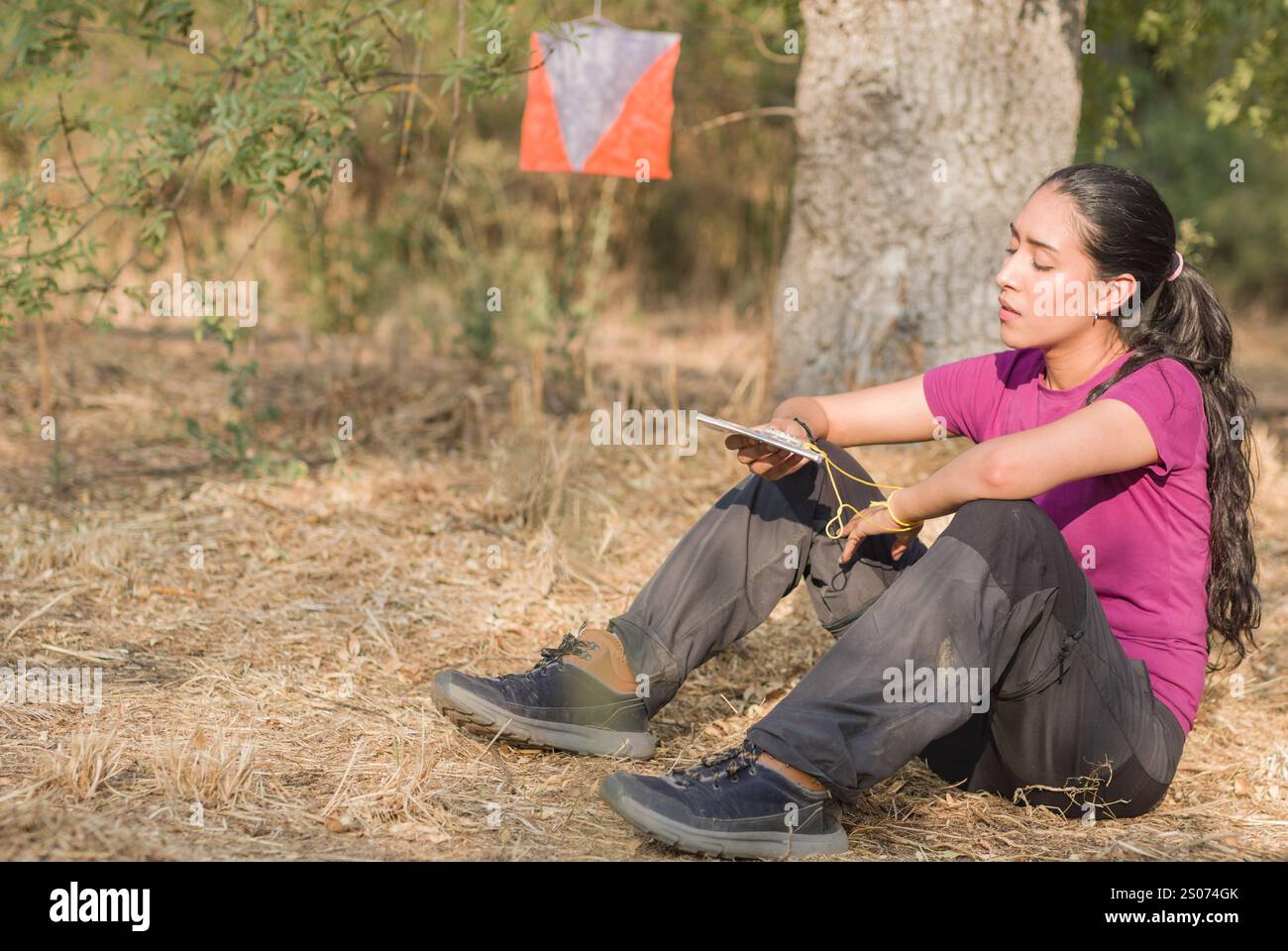 Orienteering athlete checking map and compass during race. Latin young ...