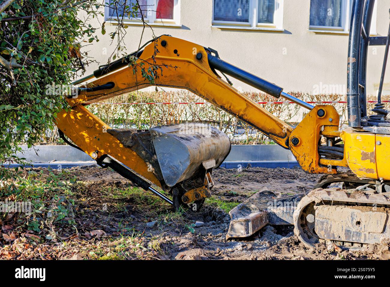 Part of a yellow, tracked mini excavator with a bucket in front of a ...