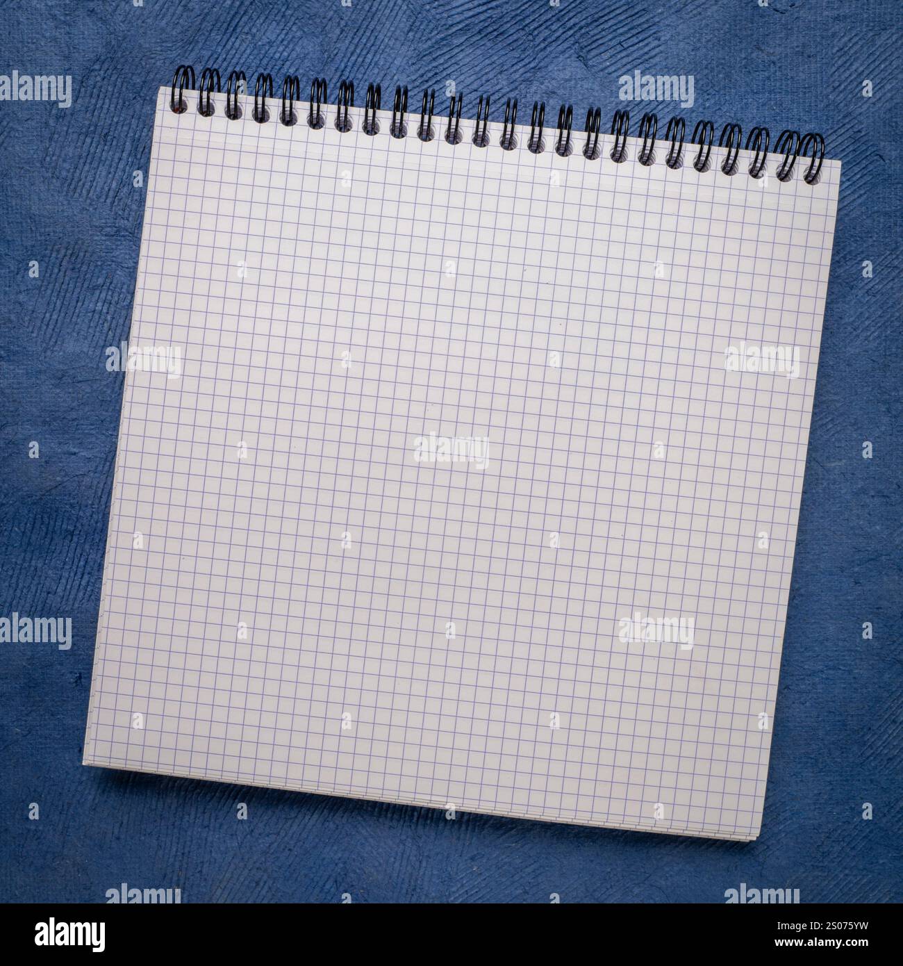 blank spiral notebook with grid paper on textured art paper Stock Photo ...